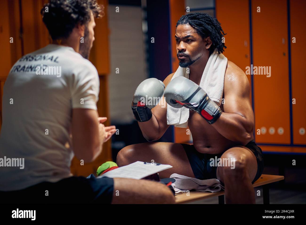 Serious boxing player sitting on bench face to face with coach getting ...