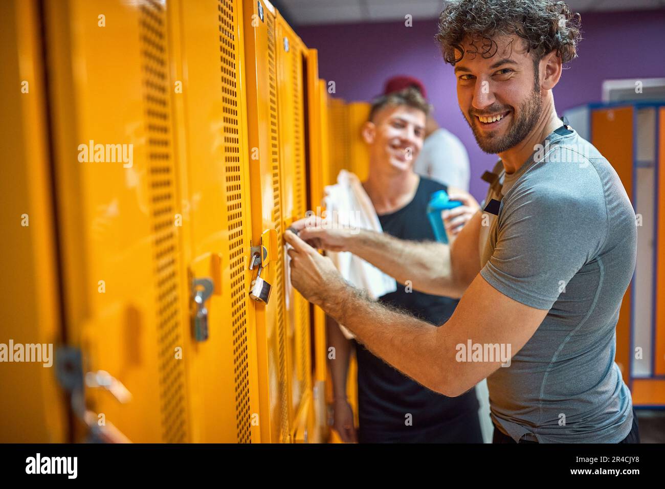 Young man in sportswear locking his locker in the dressing room, ready ...
