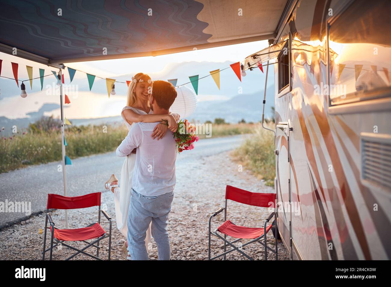 Newlywed couple in front of camper rv outdoors, man holding woman up ...