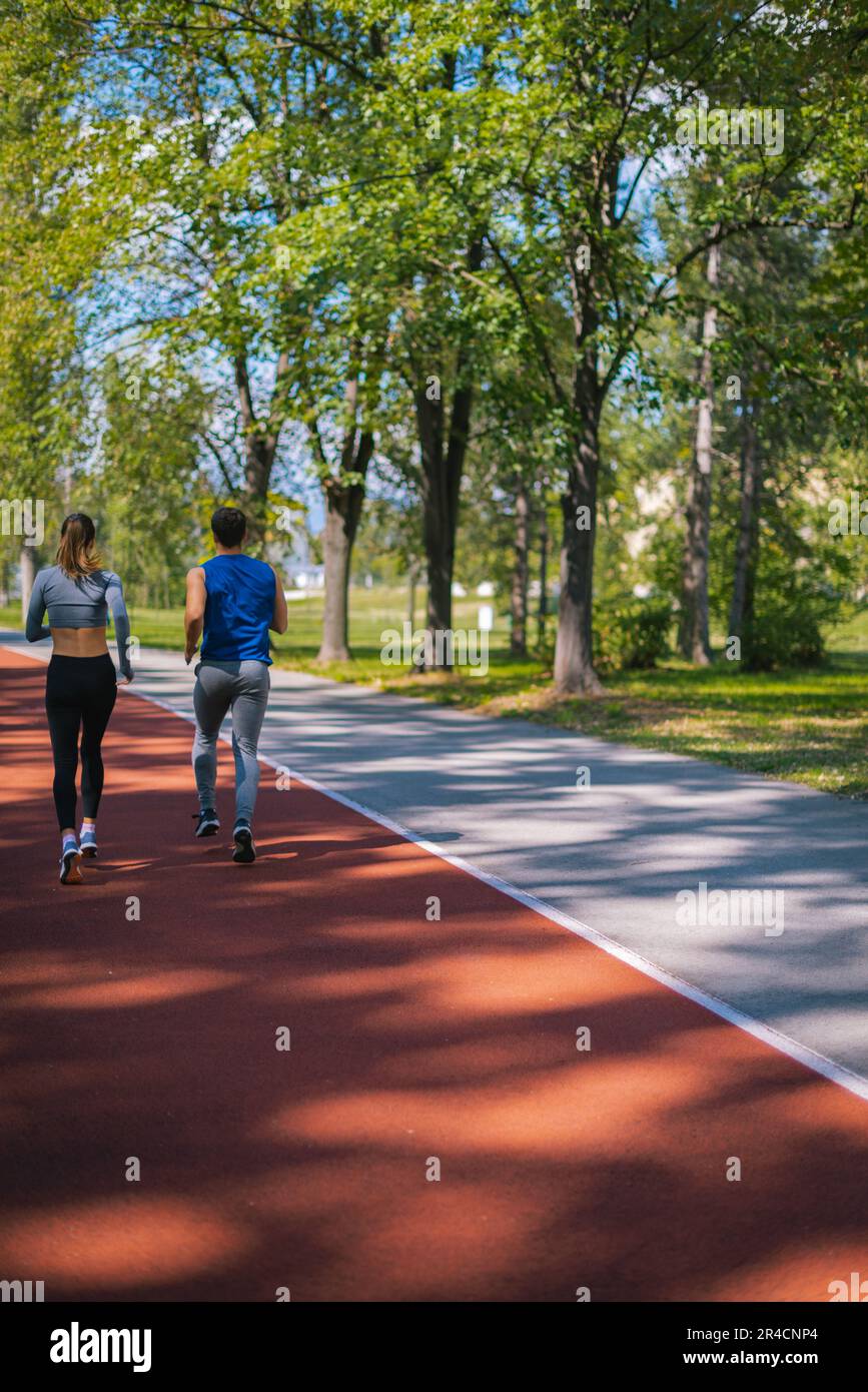 Two adult fitness models running in the park Stock Photo - Alamy