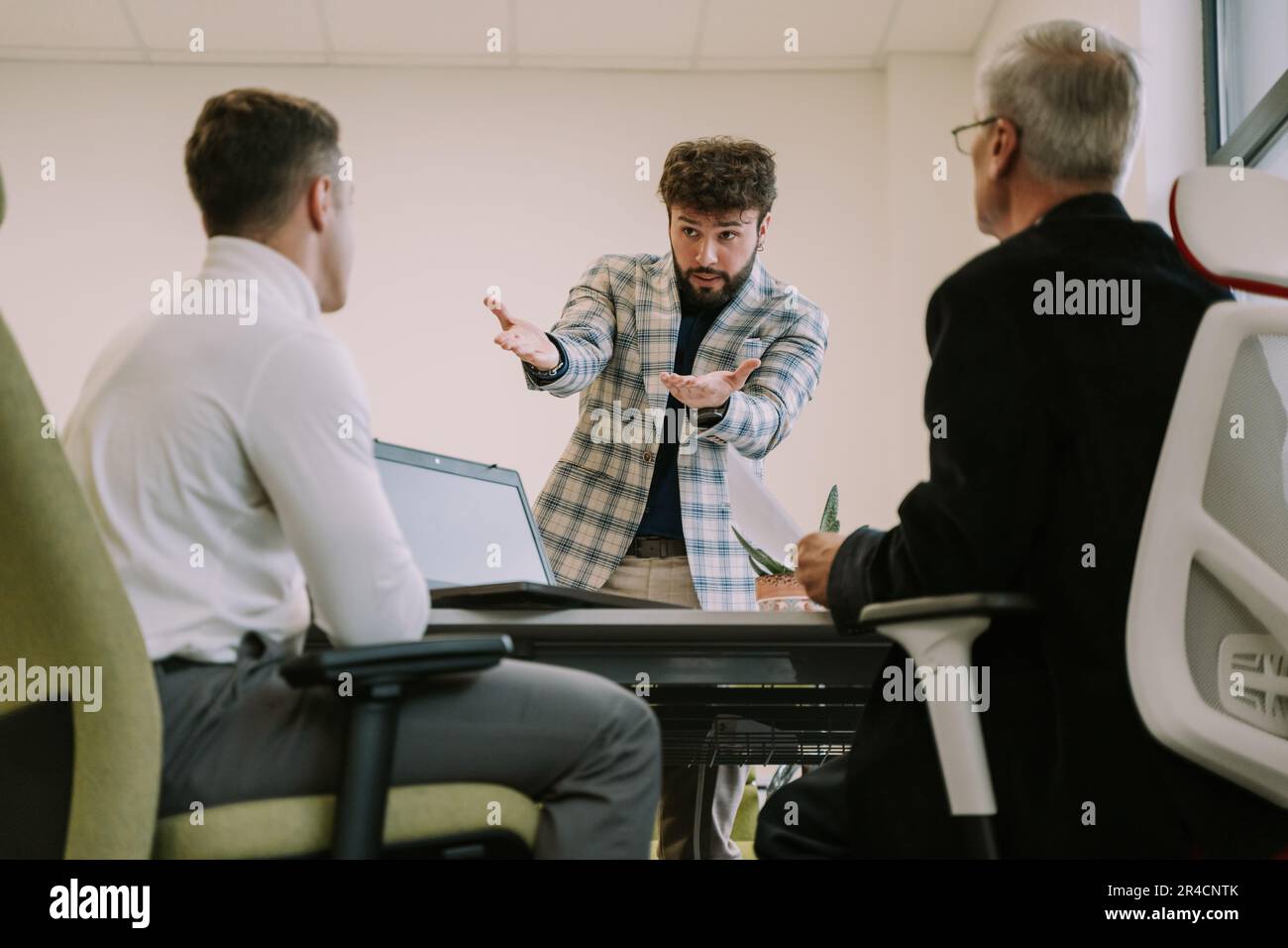 Disappointed and angry boss overlooking and correcting his employees at ...