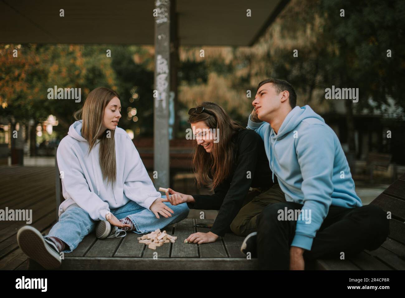 Three friends sitting on the wooden bench with scattered jenga Stock ...