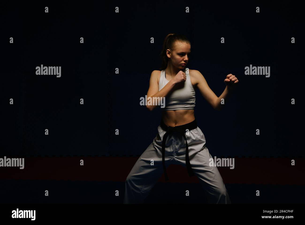 Good looking and strong girl doing Ura tsuki pose at the karate club ...