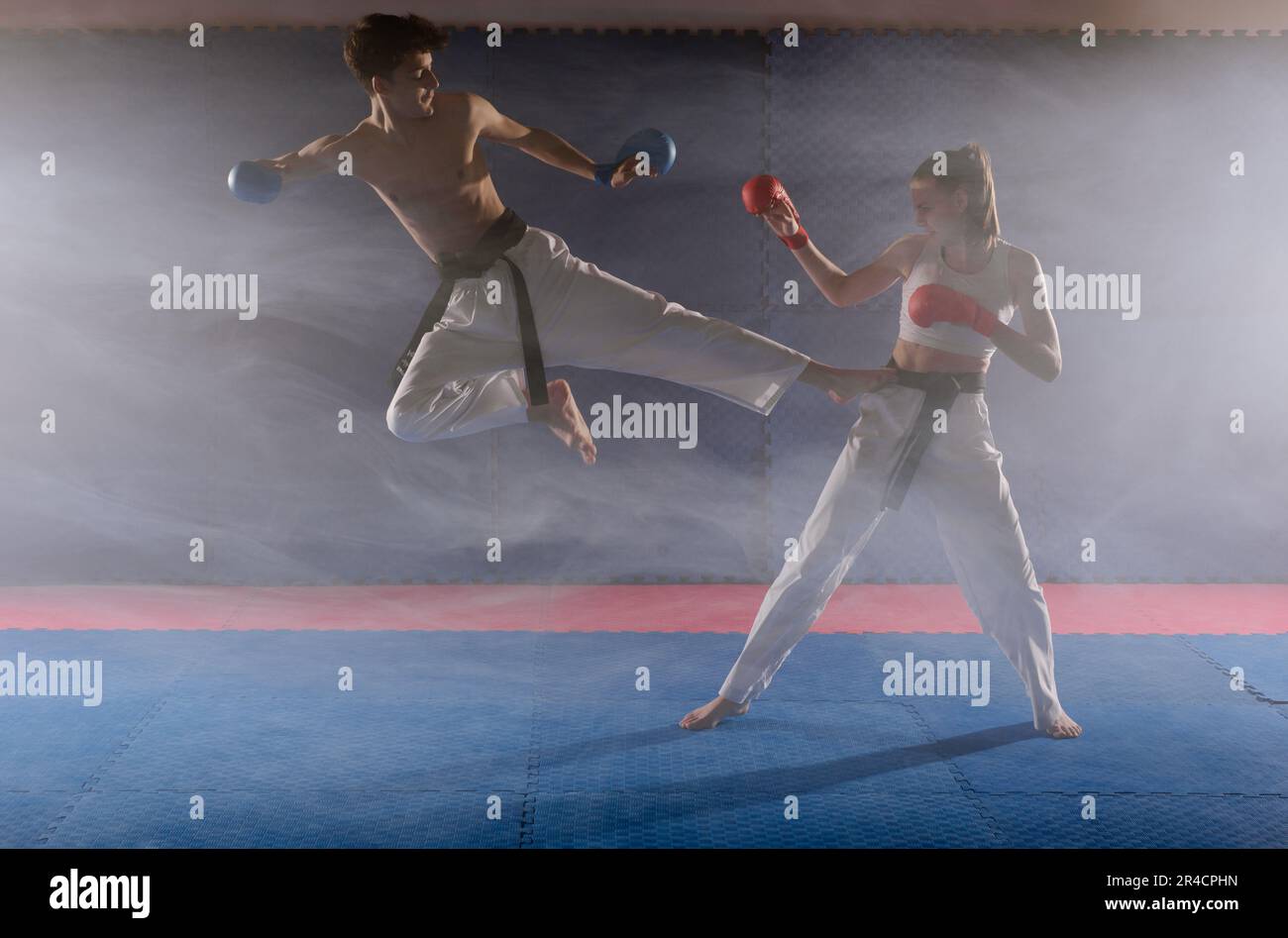 Two young karatists doing the Yoko Tobi Geri practice in the smoke at ...