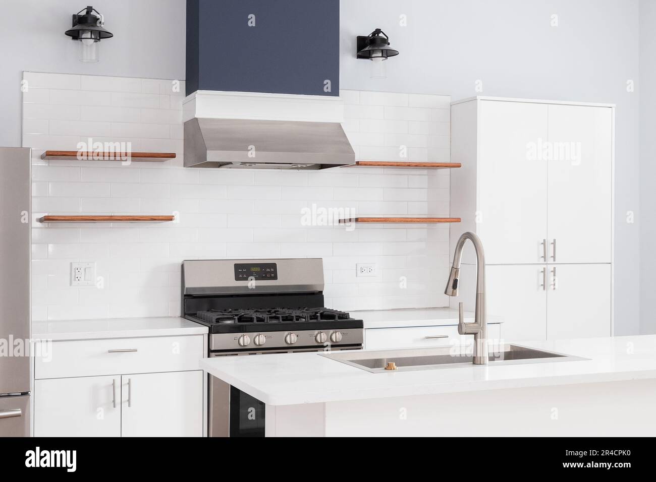 A kitchen detail with white cabinets, floating wood shelves on a white ...