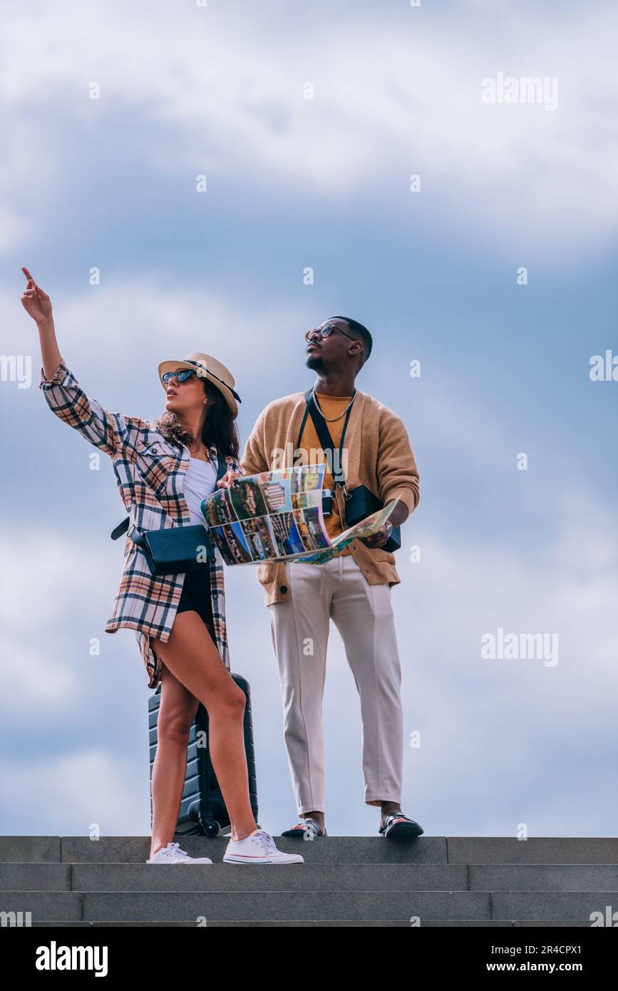 A gorgeous woman is pointing to the sky to show her boyfriend that the ...