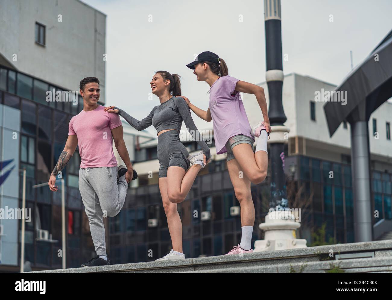 Three friends relying on each others shoulders while stretching their ...