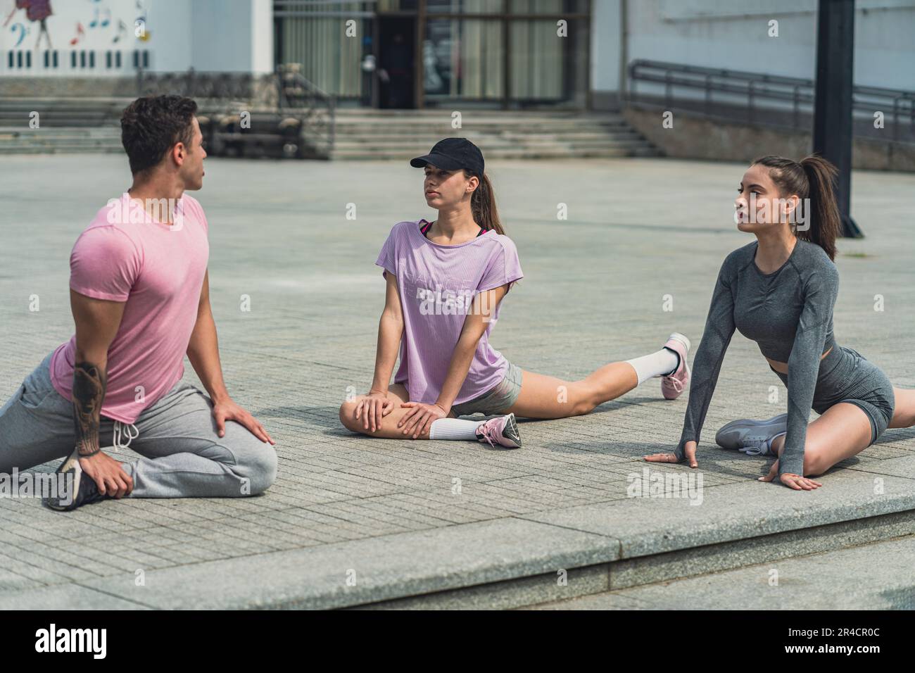 Sporty, fit friends having a conversation while stretching their legs ...