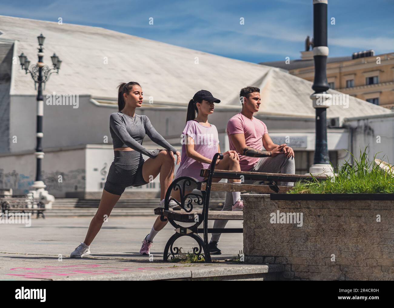 Three friends with left leg on the bench. Stretching legs before ...
