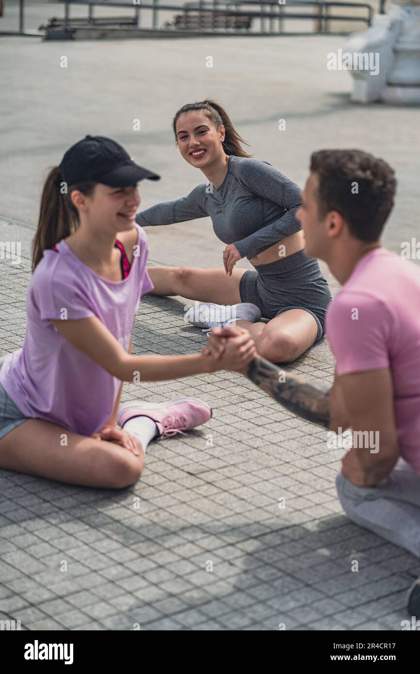 Attractive sportsgirl listening to her friends conversation and smiling ...