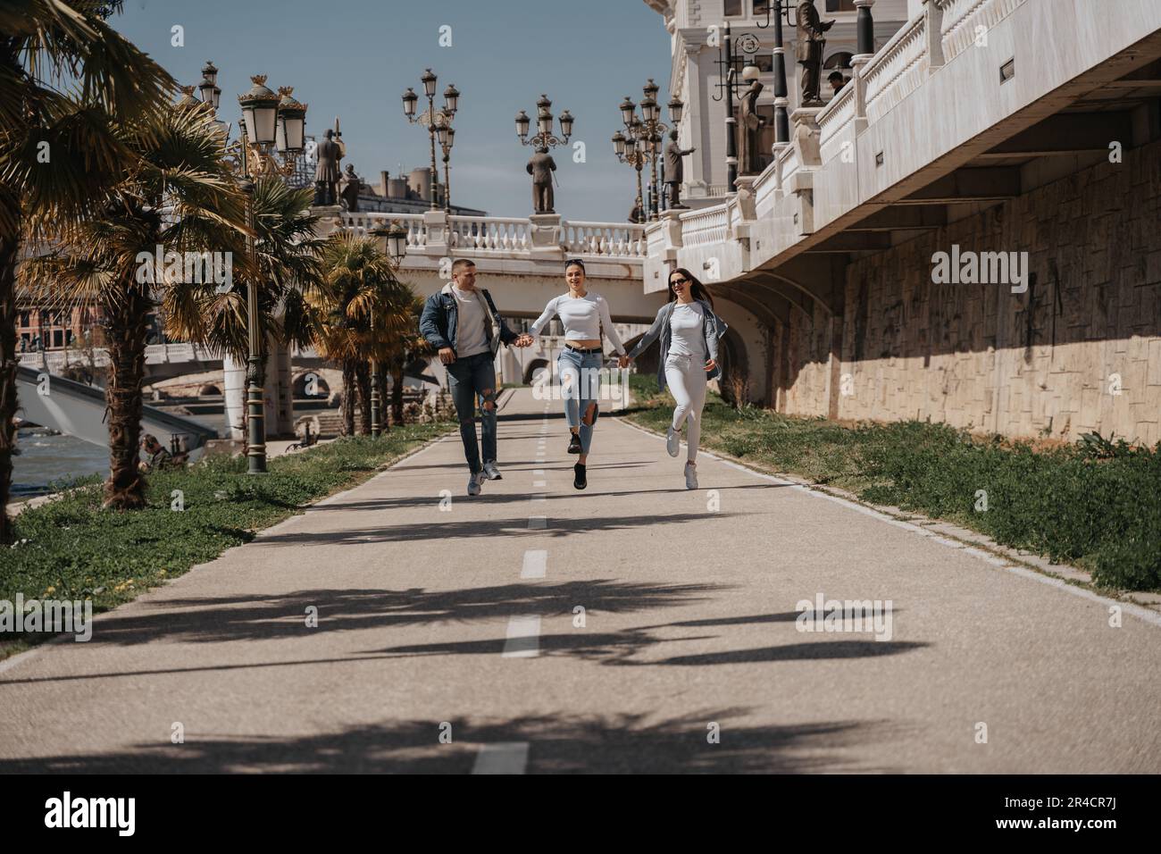 Three close friends holding hands while running together at the park ...