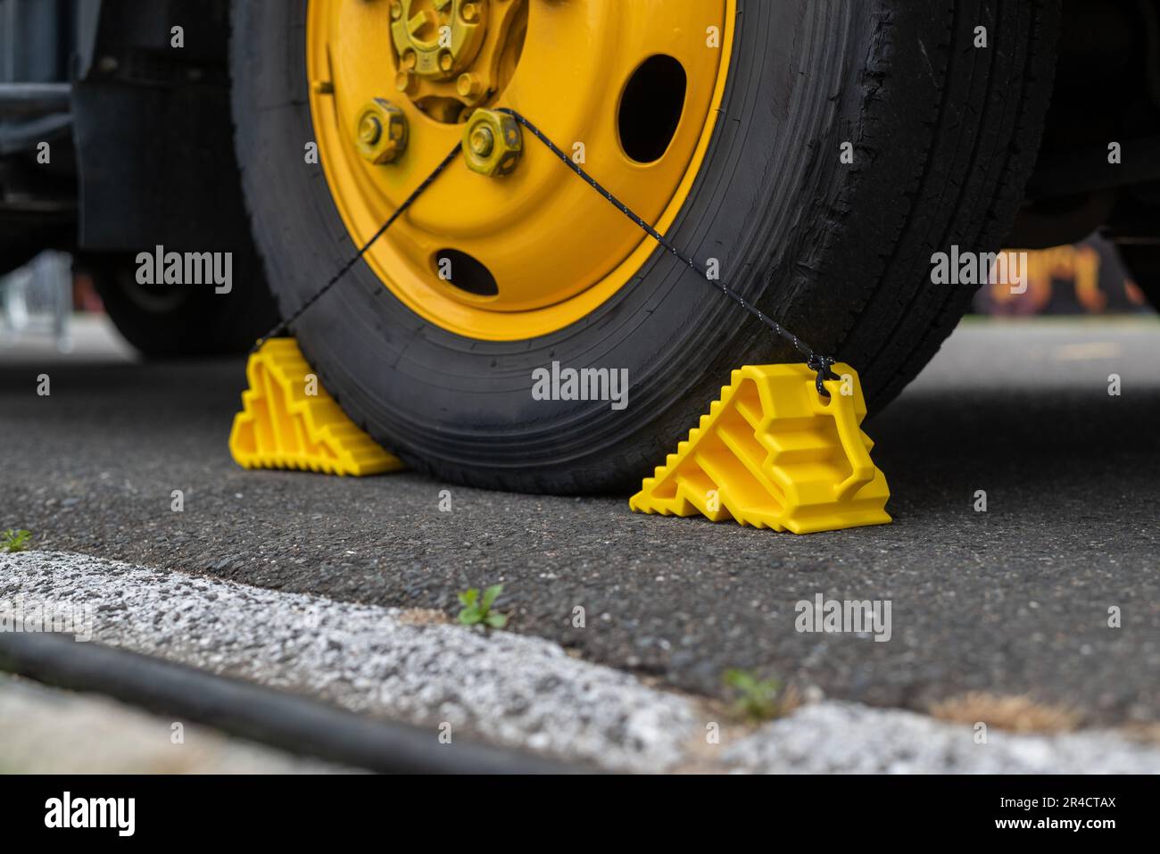 Tire stopper yellow plastic with a rope Stock Photo - Alamy