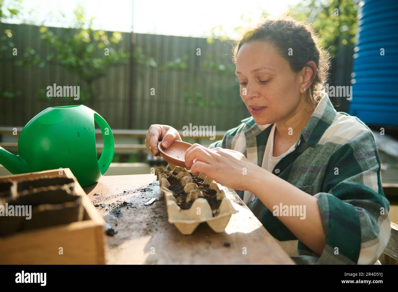 Female gardener agriculturist sorting and sowing seeds into ...