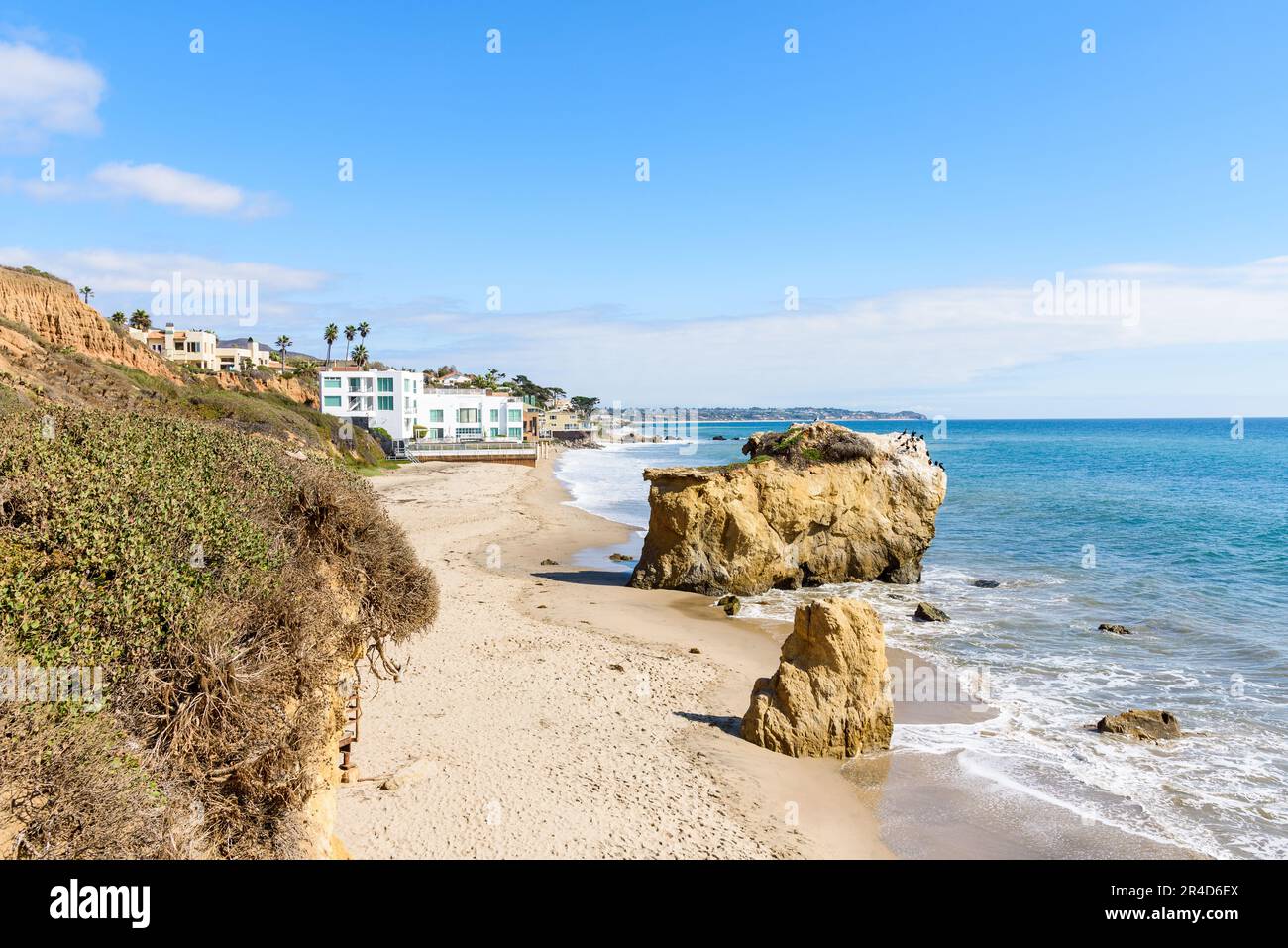 Beautiful sandy beach with sea stacks at the foot of a cliff. Modern ...