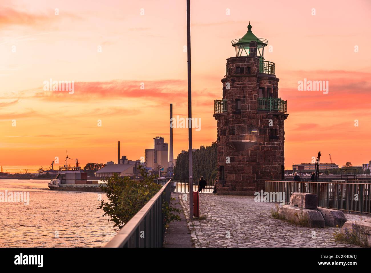 Stunning summer sunset over a historic old stone lighthouse at the end ...