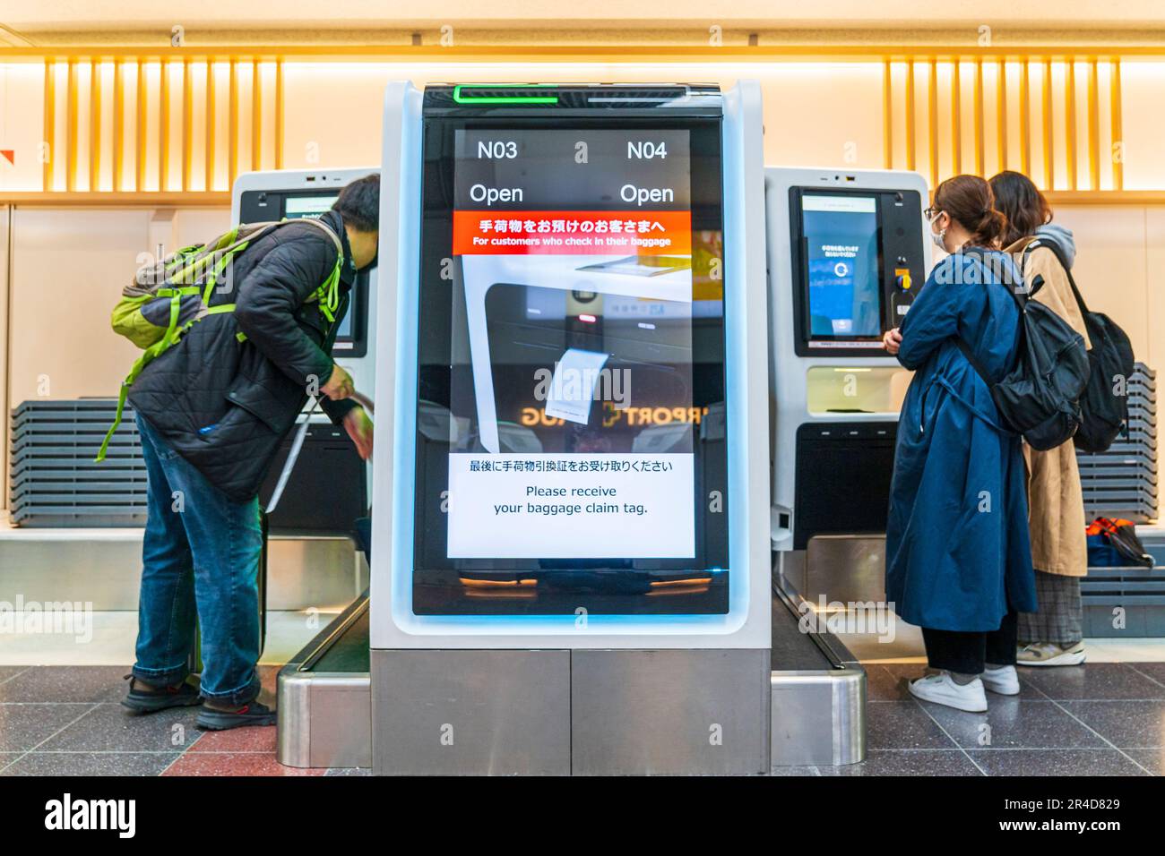 Check-in baggage machine with people checking-in using the luggage tag ...