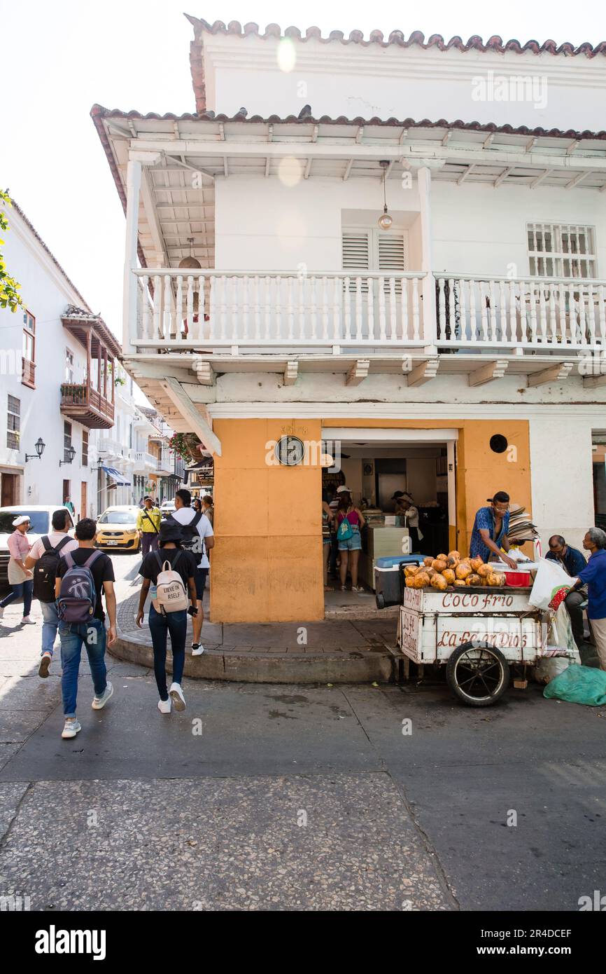People walk past a corner with a cart selling coco frio coconut water ...