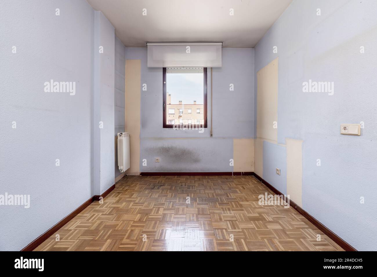 An empty room with a varnished oak parquet floor with a red aluminum ...