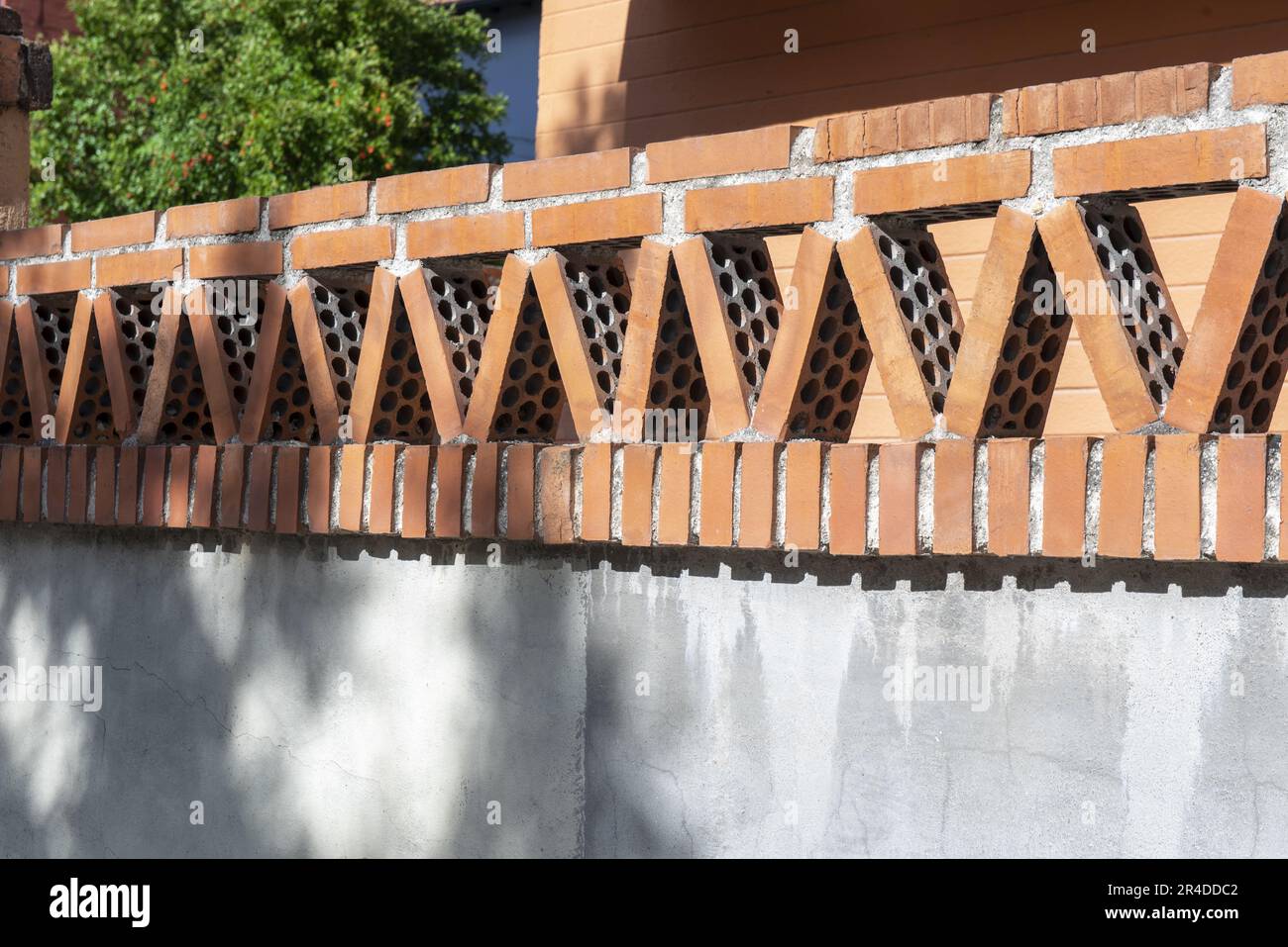 High part of a perimeter fence topped with bricks of a peculiar shape ...