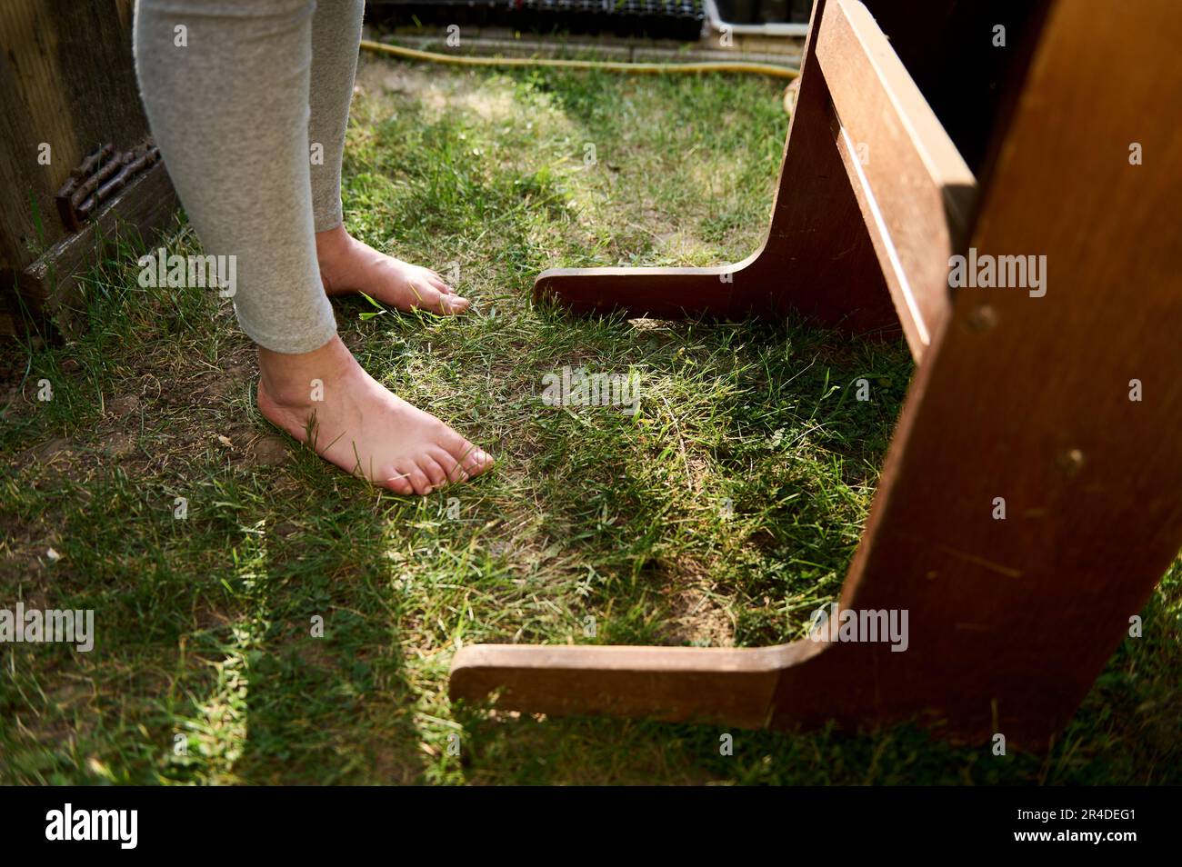 Close-up feet of a woman standing barefoot outdoors on green grass ...