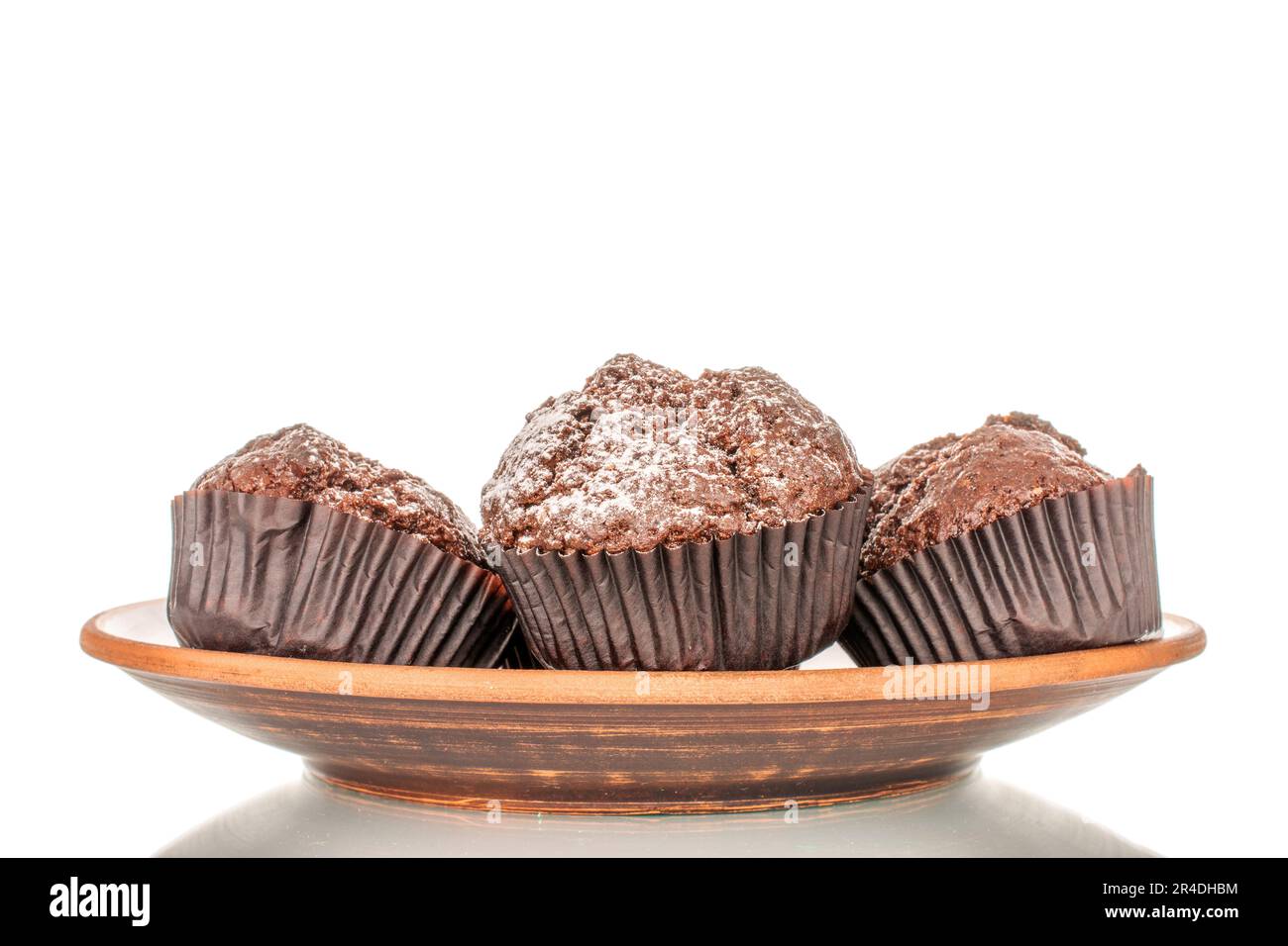 Four homemade chocolate muffins on a clay plate, macro, isolated on ...