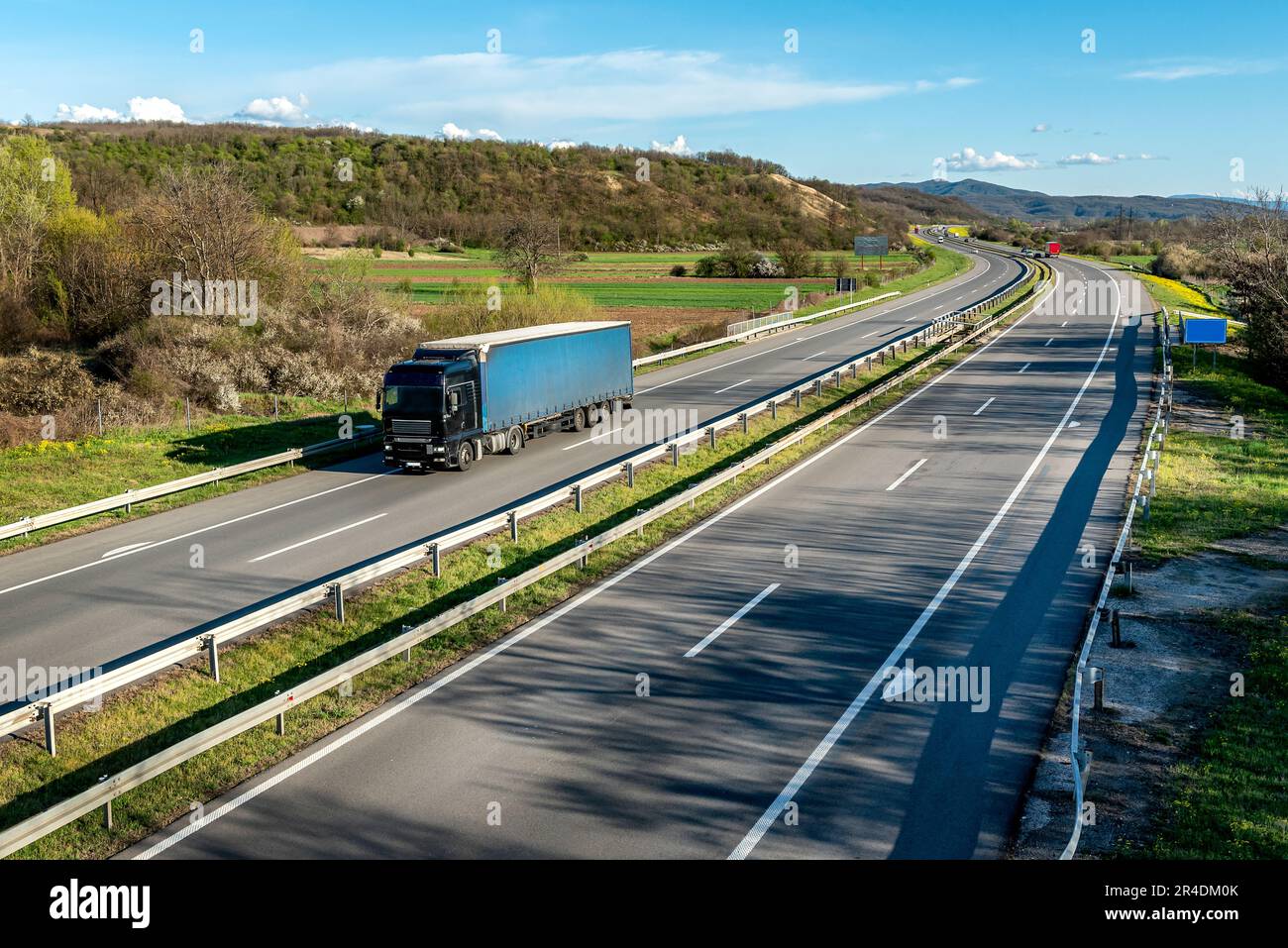 Highway transportation scene with blue transportation truck on a rural ...