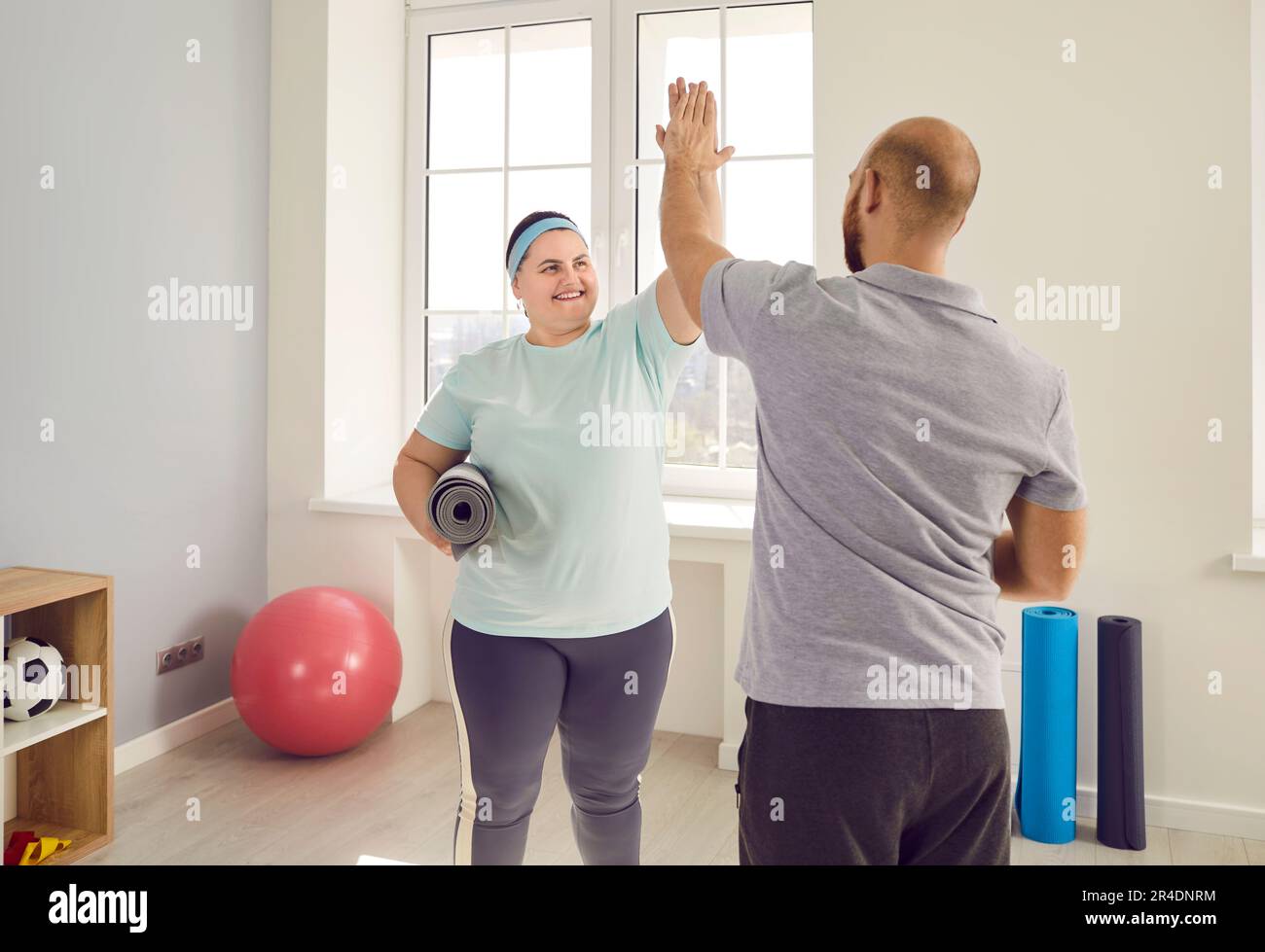 Happy, overweight woman and her personal sports trainer give each other ...