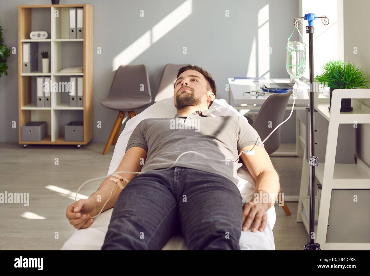 Man lying on the couch in clinic and receiving IV drip infusion and ...