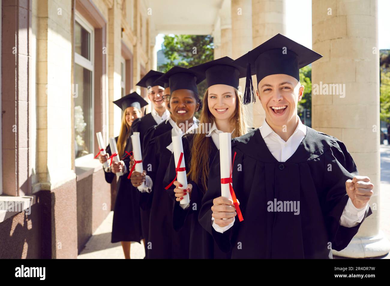 College graduates standing behind each other and smiling Stock Photo ...