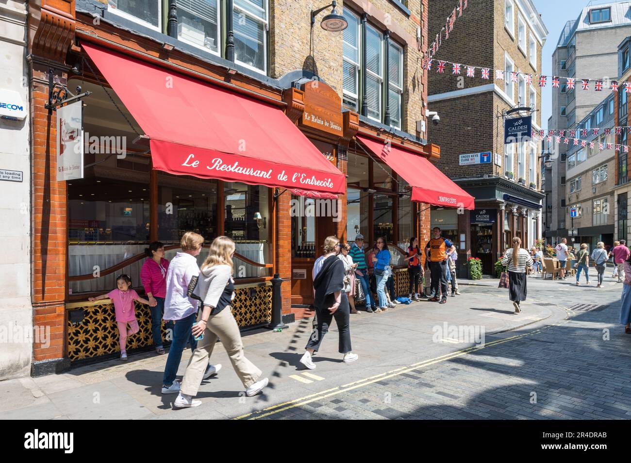People out and about on a sunny early summer day pass by Le Relais de ...