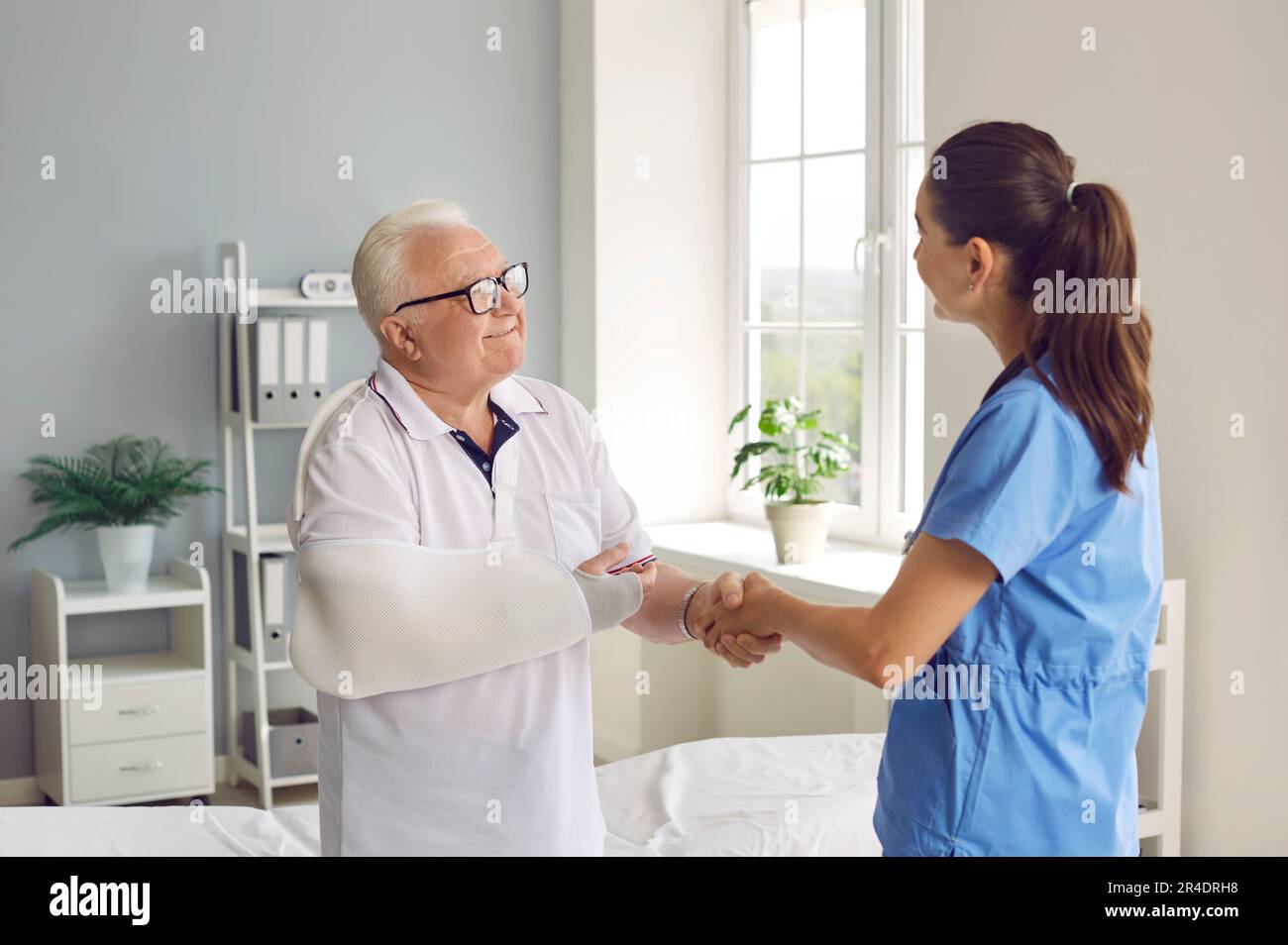 Happy patient with broken arm shaking hands with doctor, thanking for ...