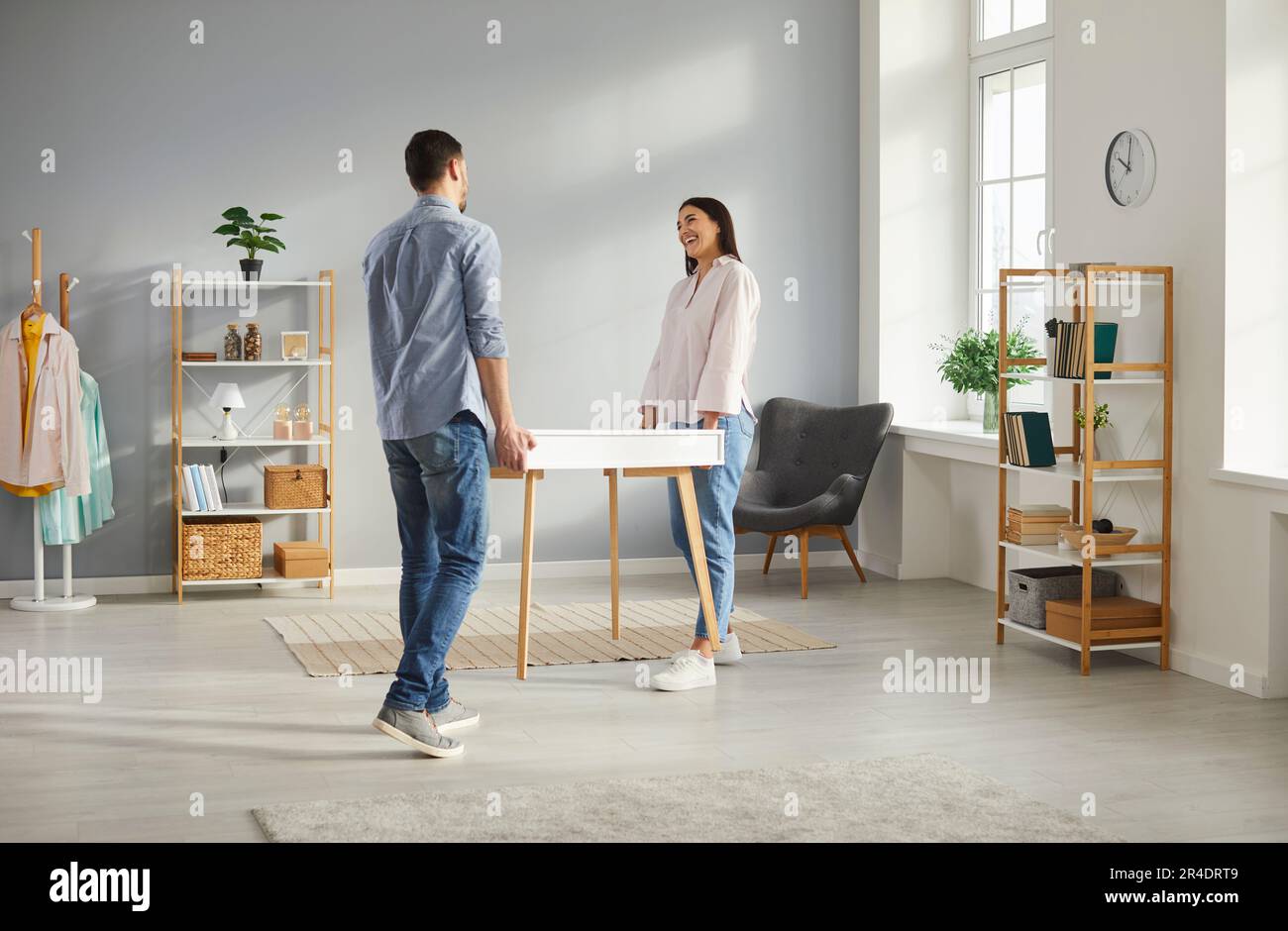 Happy young husband and wife moving furniture and carrying a new table ...