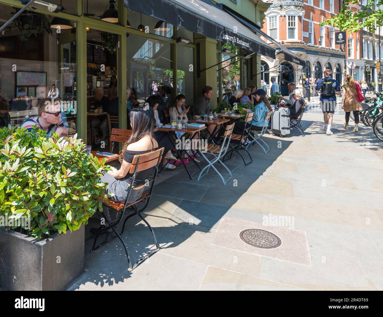 People enjoying food and drink seated at pavement tables outside Le ...