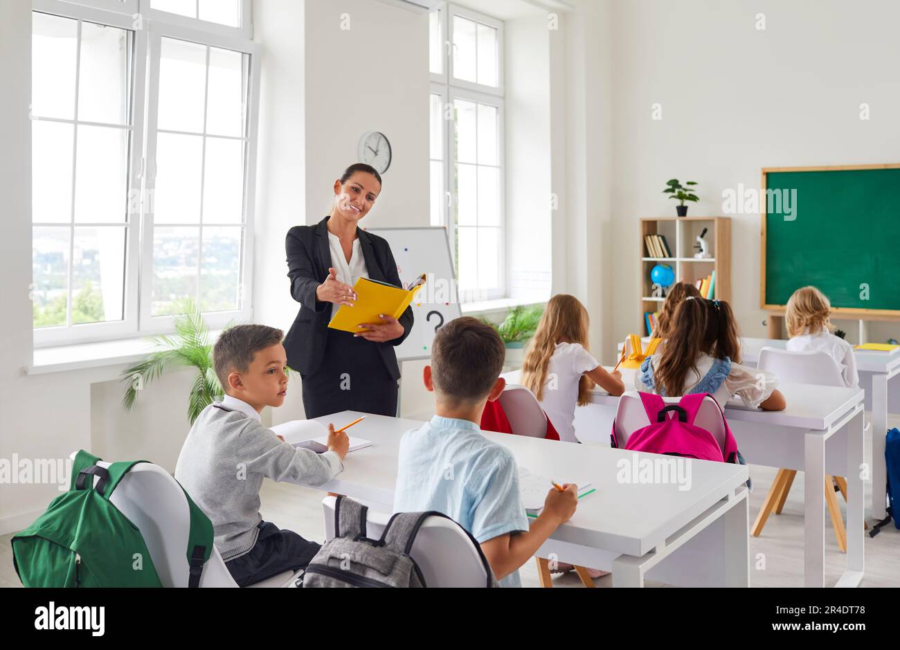 Cheerful female teacher teaching kids in classroom at school Stock ...