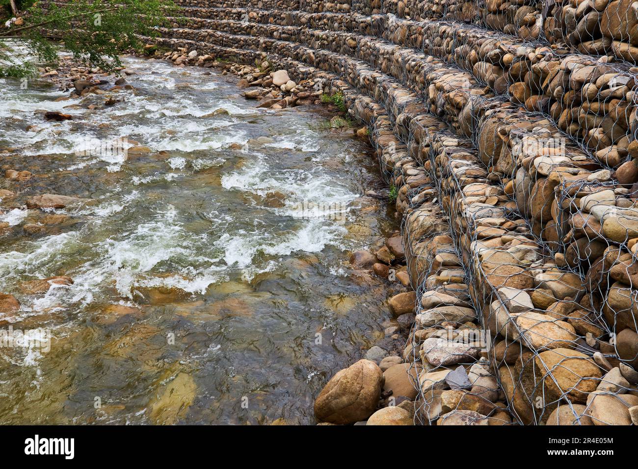 Strengthening the banks of the mountain river, mesh and stones ...