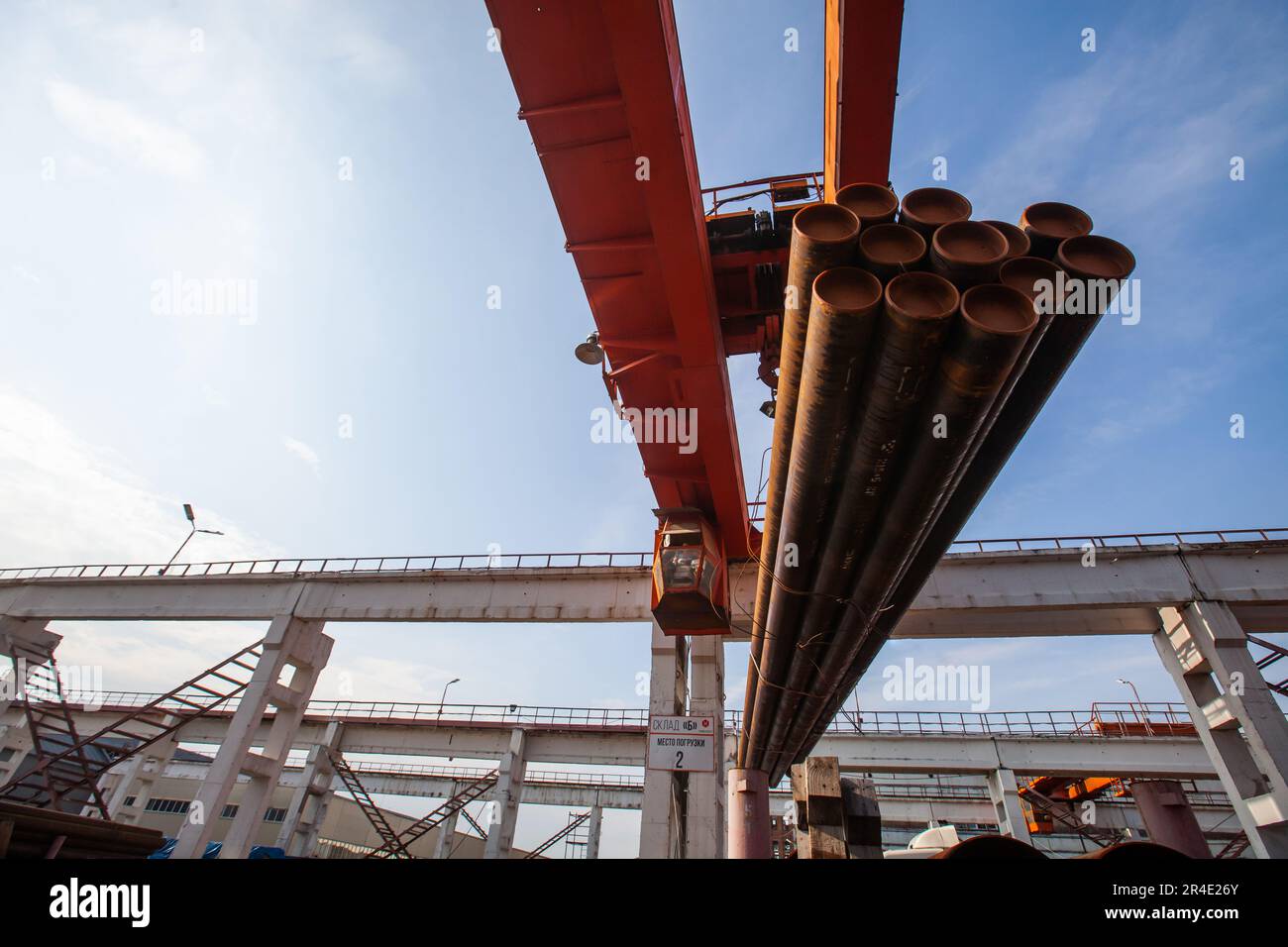 Overhead crane move steel pipes. Outdoor warehouse. Wide-angle view ...