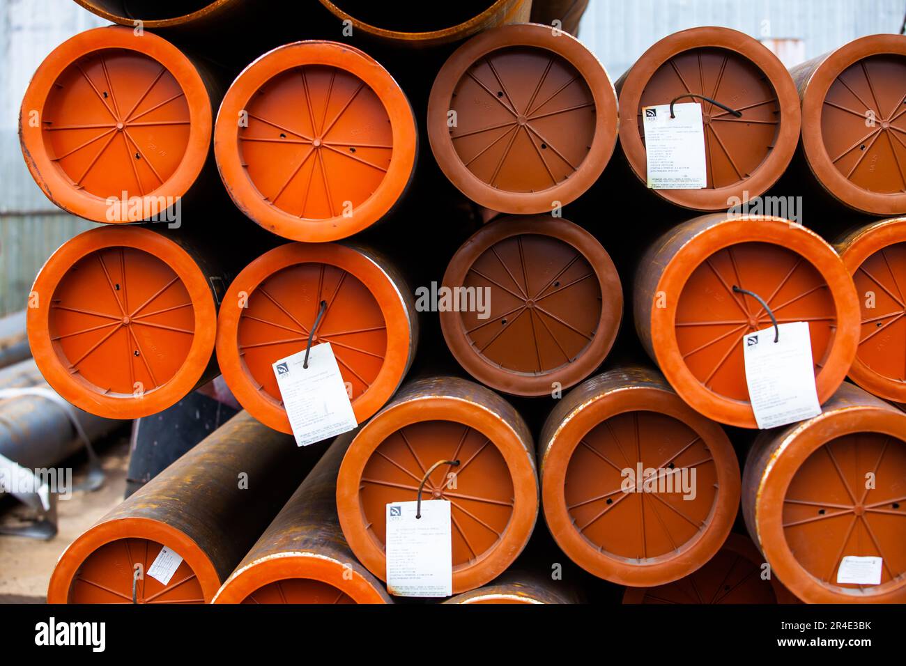 Steel pipes with plastic caps on outdoor warehouse Stock Photo - Alamy