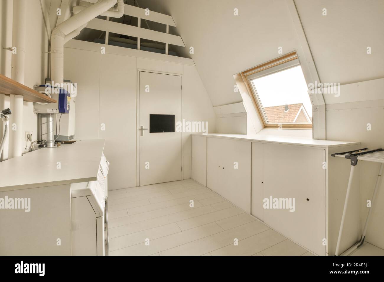 a kitchen area in an attic style house with white walls and wood trim ...