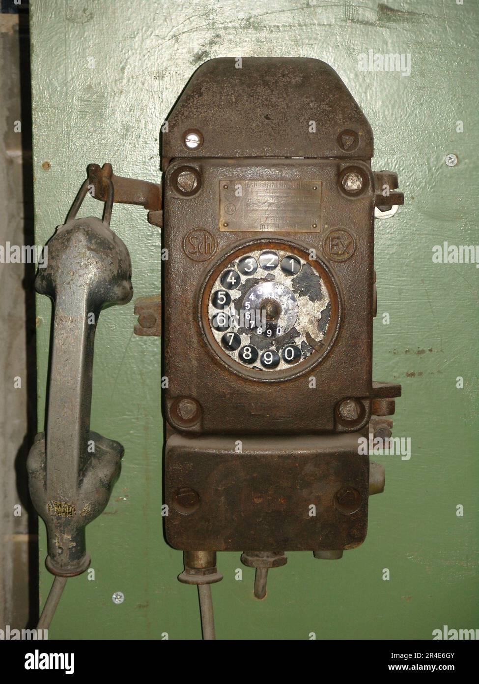 A vintage rotary telephone mounted on a wall in a dilapidated building ...