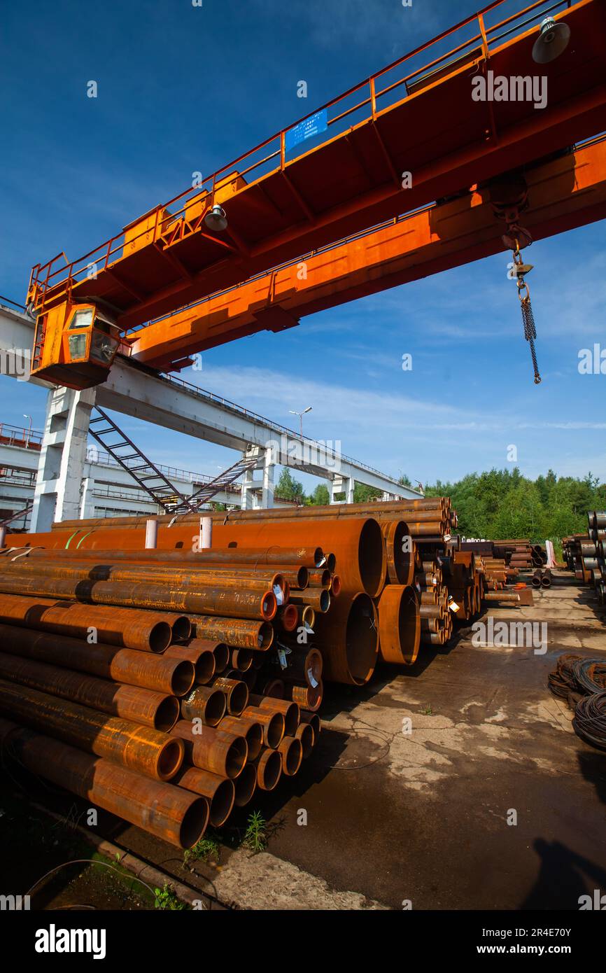 Rusted steel pipes and tubes on outdoor warehouse. Overhead crane on ...