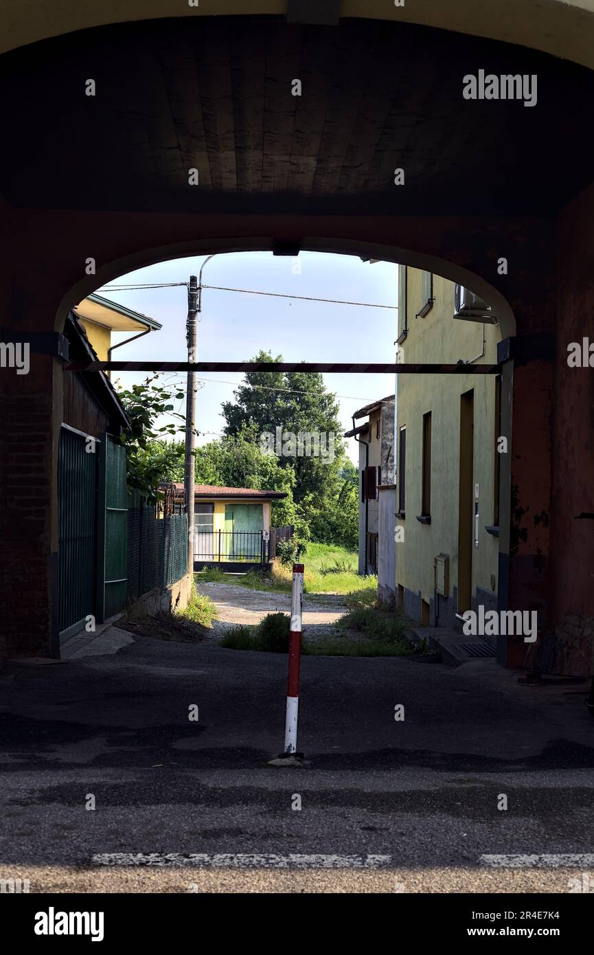 Covered alley between buildings that leads to a path next to a field on ...