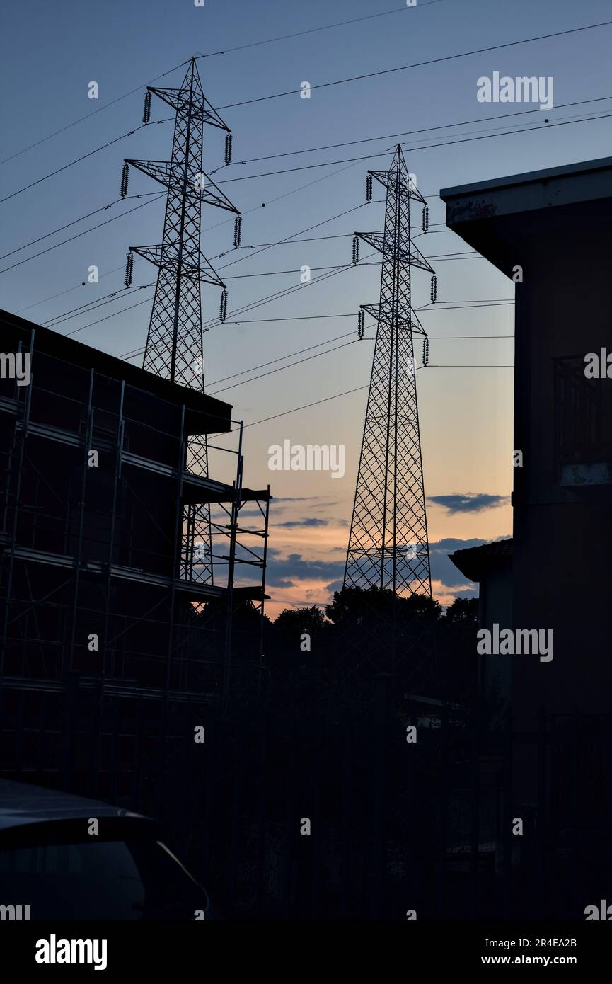 Electricity pylons at sunset framed by buildings Stock Photo - Alamy