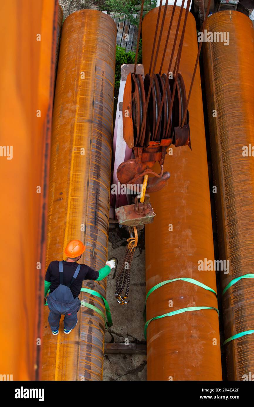 Worker, rusted tubes and crane hook Stock Photo - Alamy