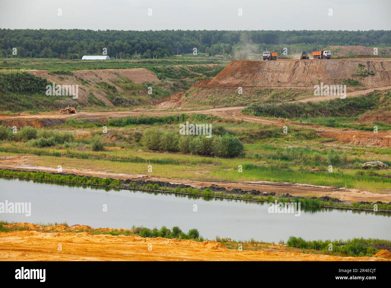 Landfill on old quarry. Dump trucks unloads garbage. Water and trees ...