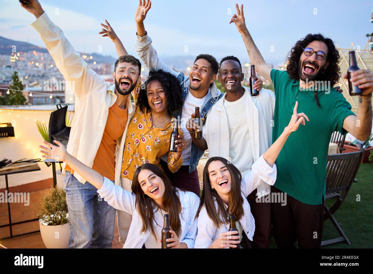 Group of diverse excited friends celebrating with beers at barbecue ...