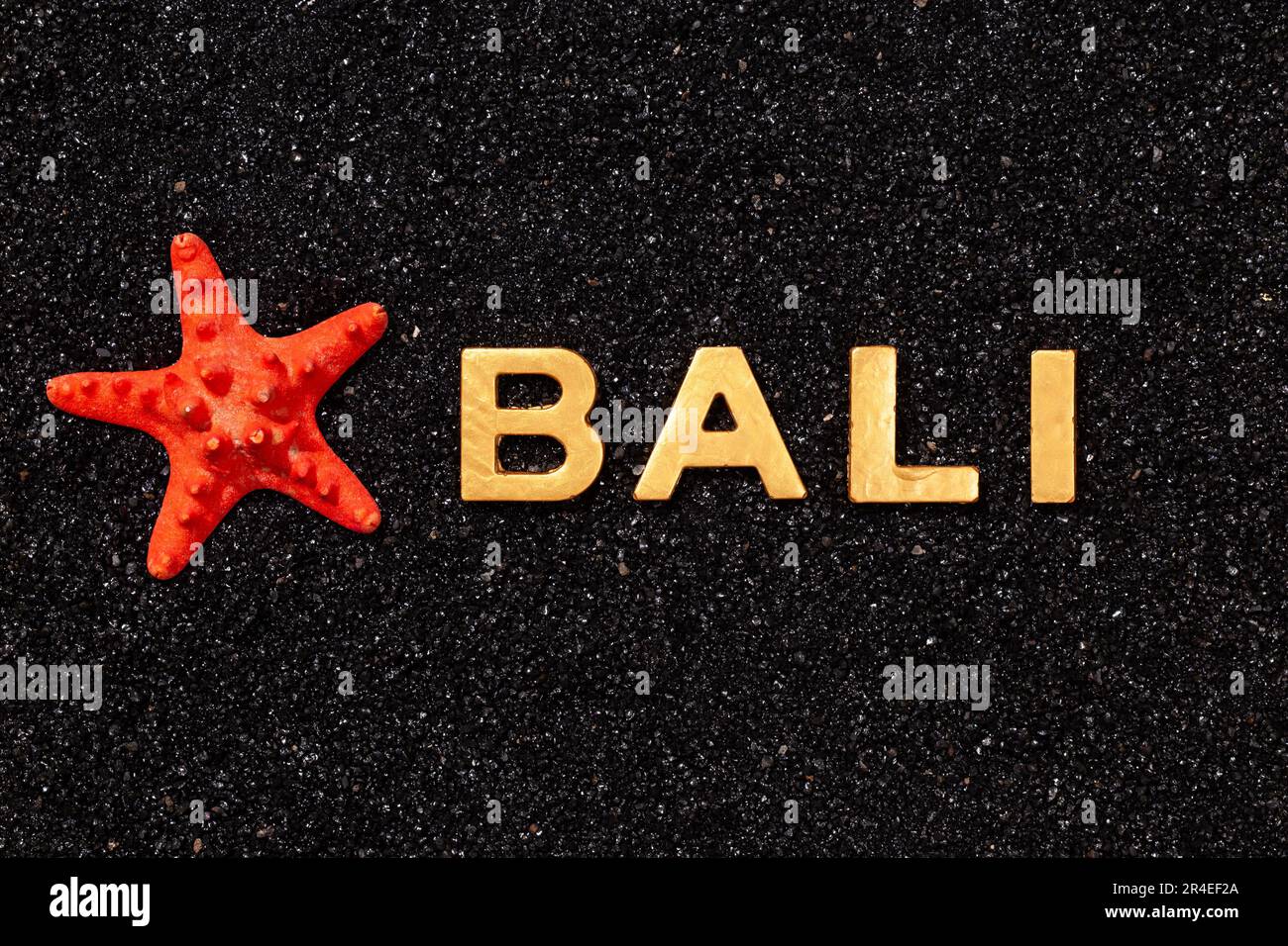Bali - Name of Indonesian island in black sand and red starfish Stock ...