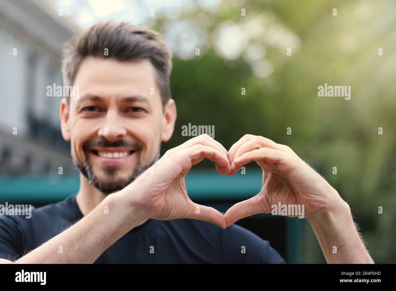 Happy man making heart with hands outdoors Stock Photo - Alamy