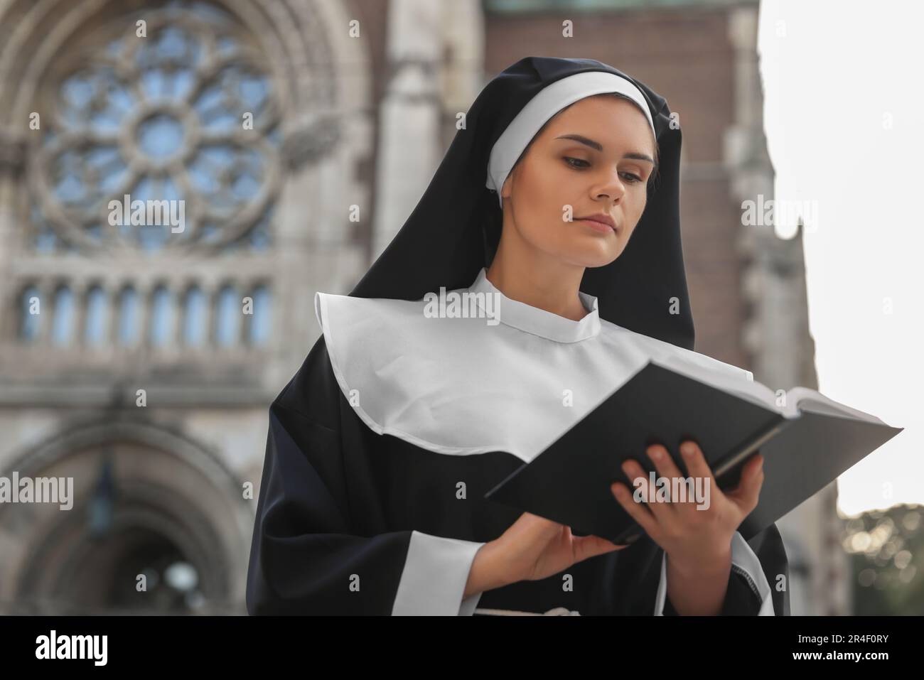 Young nun reading Bible near cathedral outdoors Stock Photo - Alamy