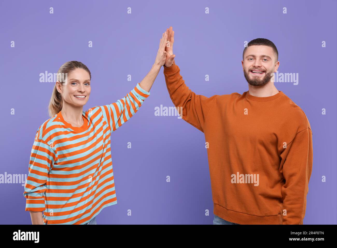 Happy couple giving high five on purple background Stock Photo - Alamy