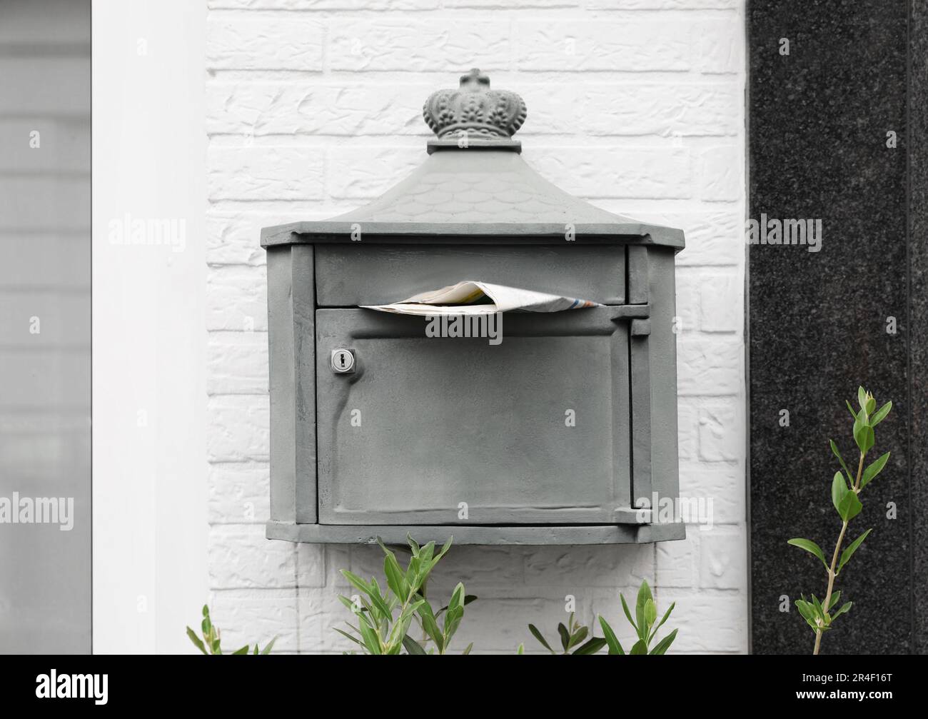 Metal letter box with newspaper on white brick wall outdoors Stock ...